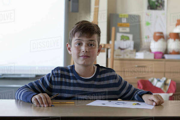 Boy with drawing paper in classroom, portrait - Stock Photo - Dissolve