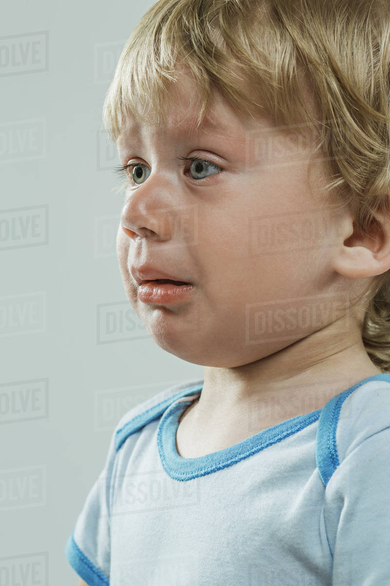 Cute boy crying over gray background - Stock Photo - Dissolve