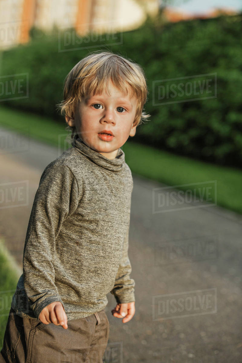 Portrait of cute boy standing on footpath - Stock Photo - Dissolve