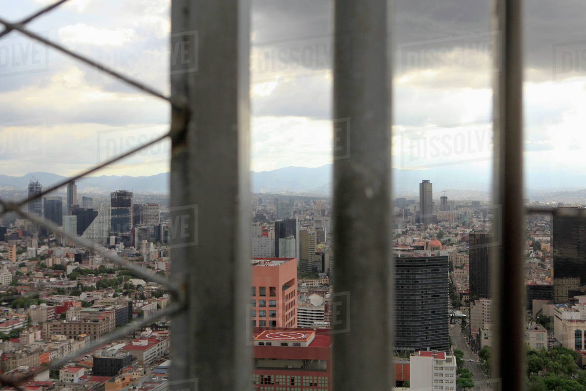 Cityscape seen through window against cloudy sky - Stock Photo - Dissolve