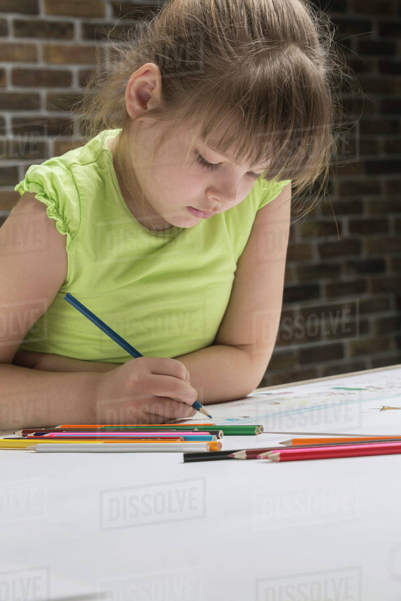 Girl drawing at table against brick wall in house - Royalty-free Stock ...