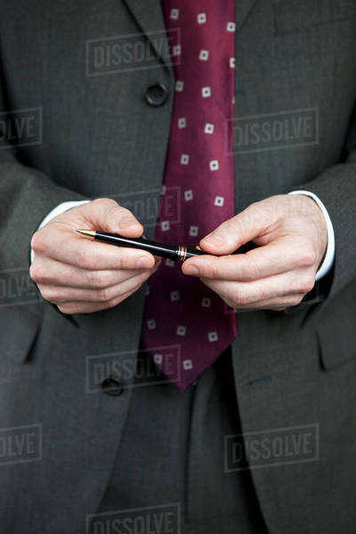 Businessman holding pen close up - Stock Photo - Dissolve