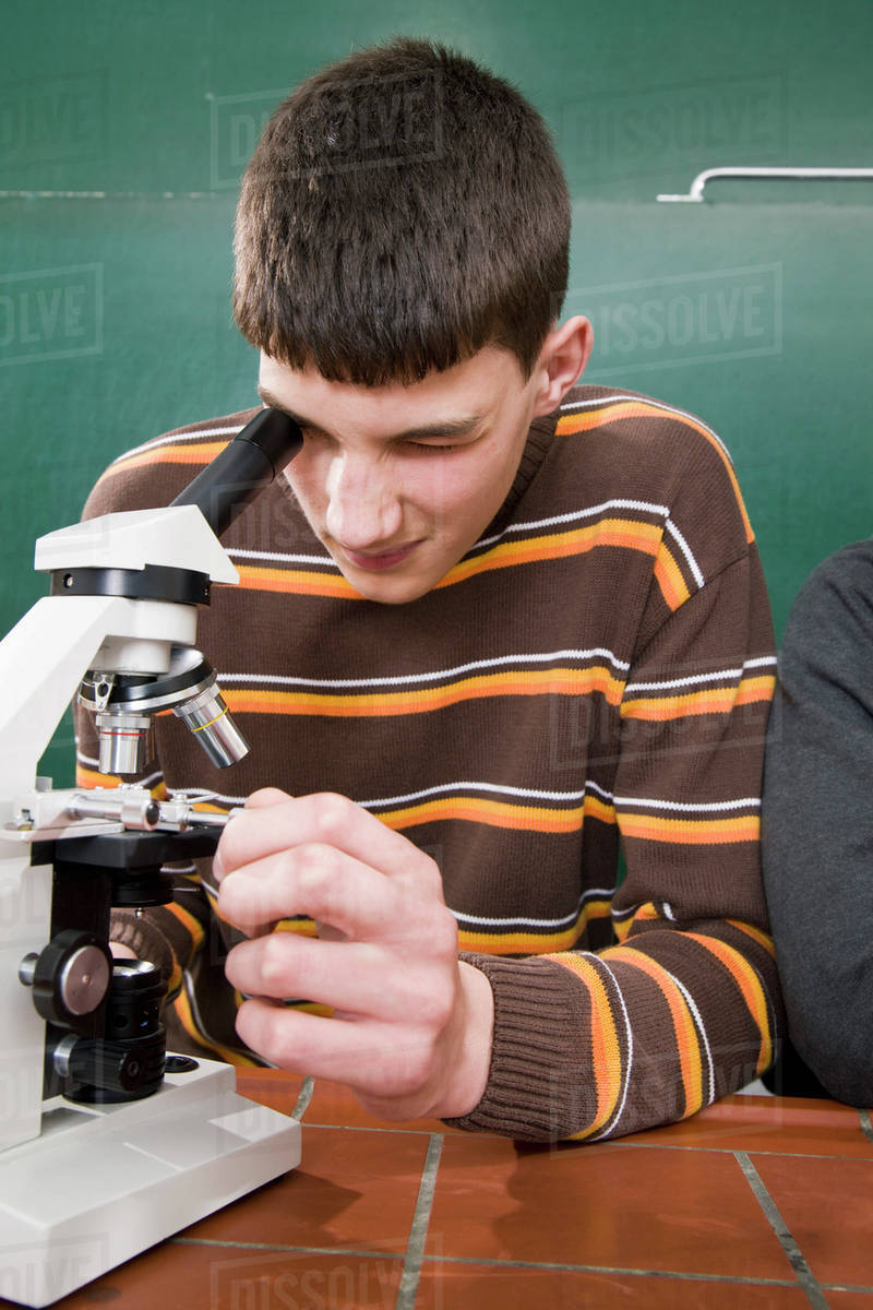 A student looking through a microscope in biology class - Royalty-free ...