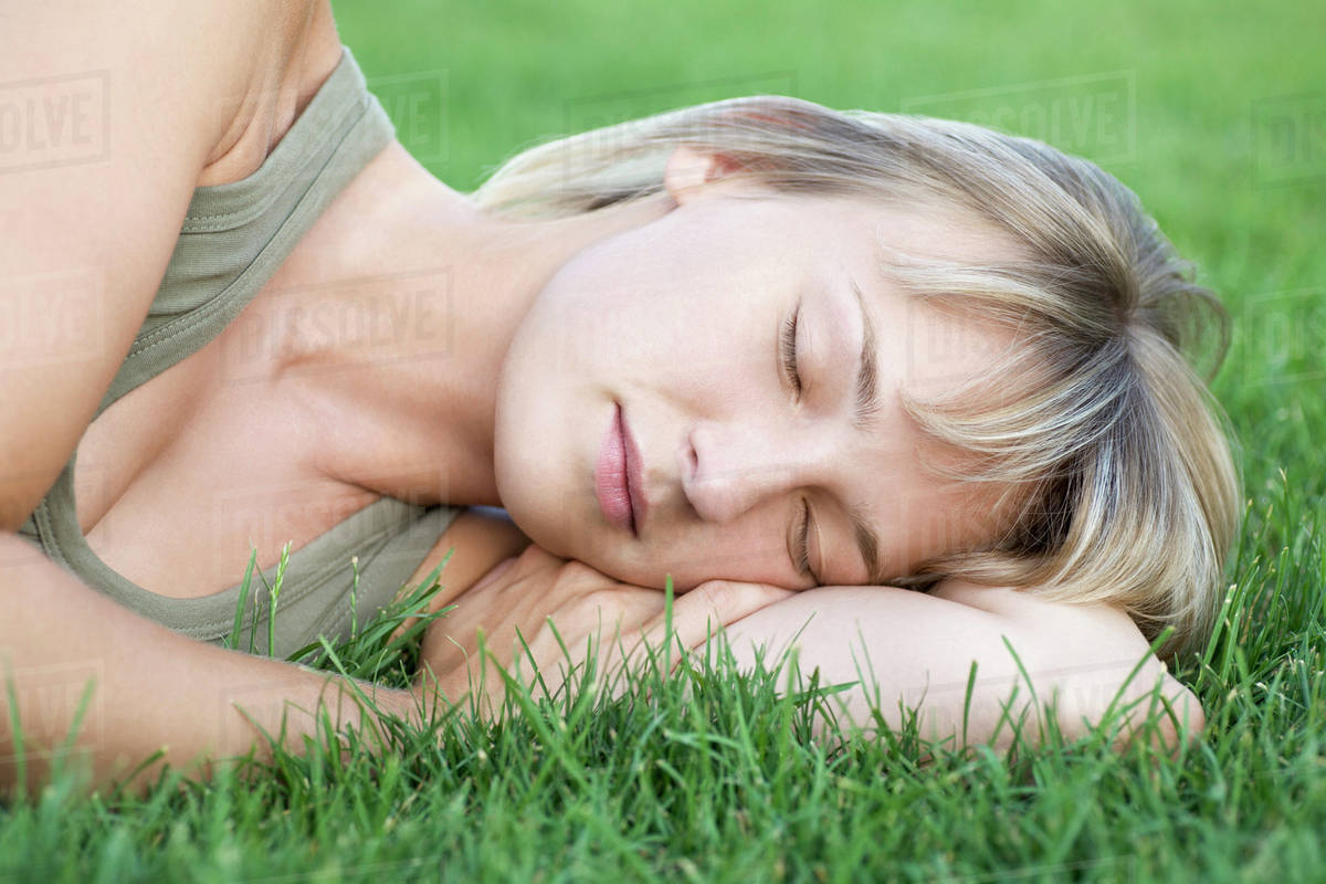 Woman sleeping on arm on grass - Stock Photo - Dissolve