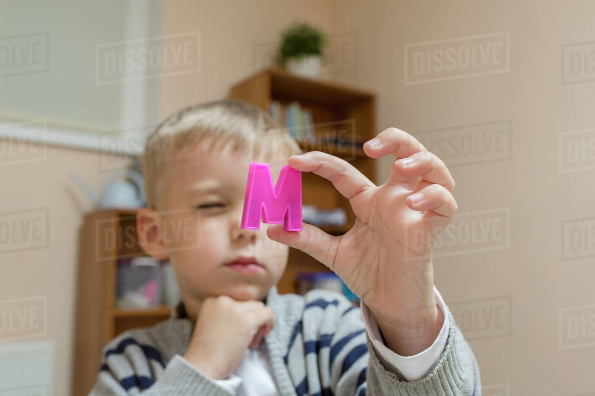 Close-up of boy holding letter M - Royalty-free Stock Photo | Dissolve