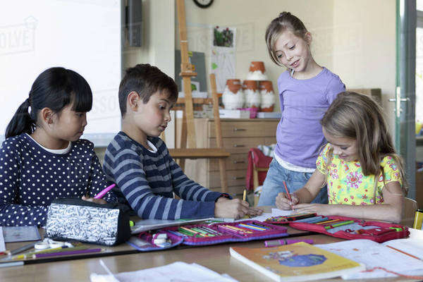 Students drawing on paper in classroom - Stock Photo - Dissolve