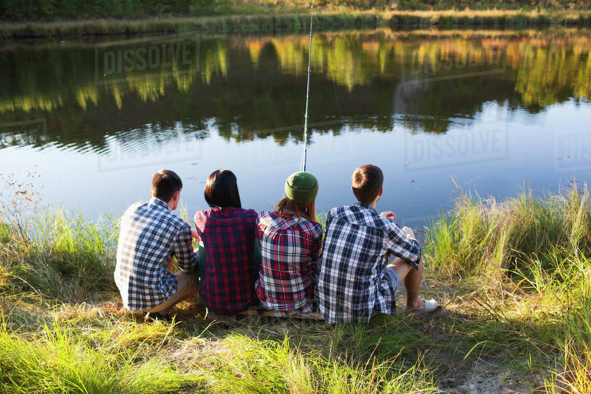 Rear view of friends fishing at lakeshore - Royalty-free Stock Photo ...