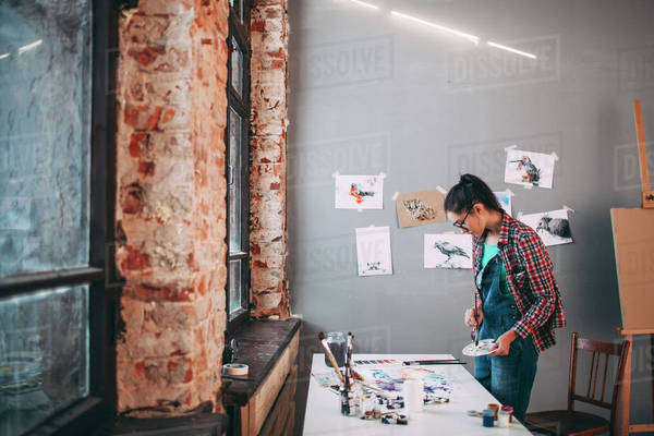 Side view of artist painting at table in art studio - Royalty-free ...