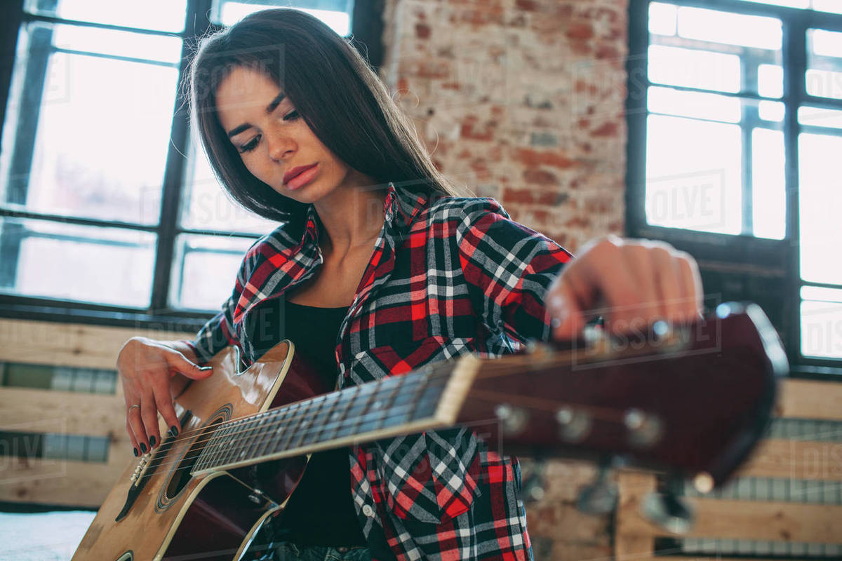Low angle view of young woman playing guitar at home - Royalty-free ...