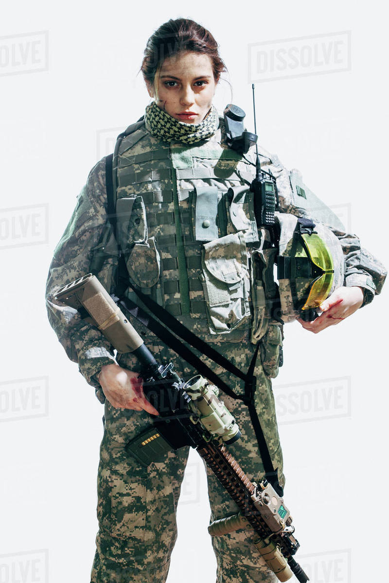 Portrait of soldier holding rifle and helmet standing against white ...
