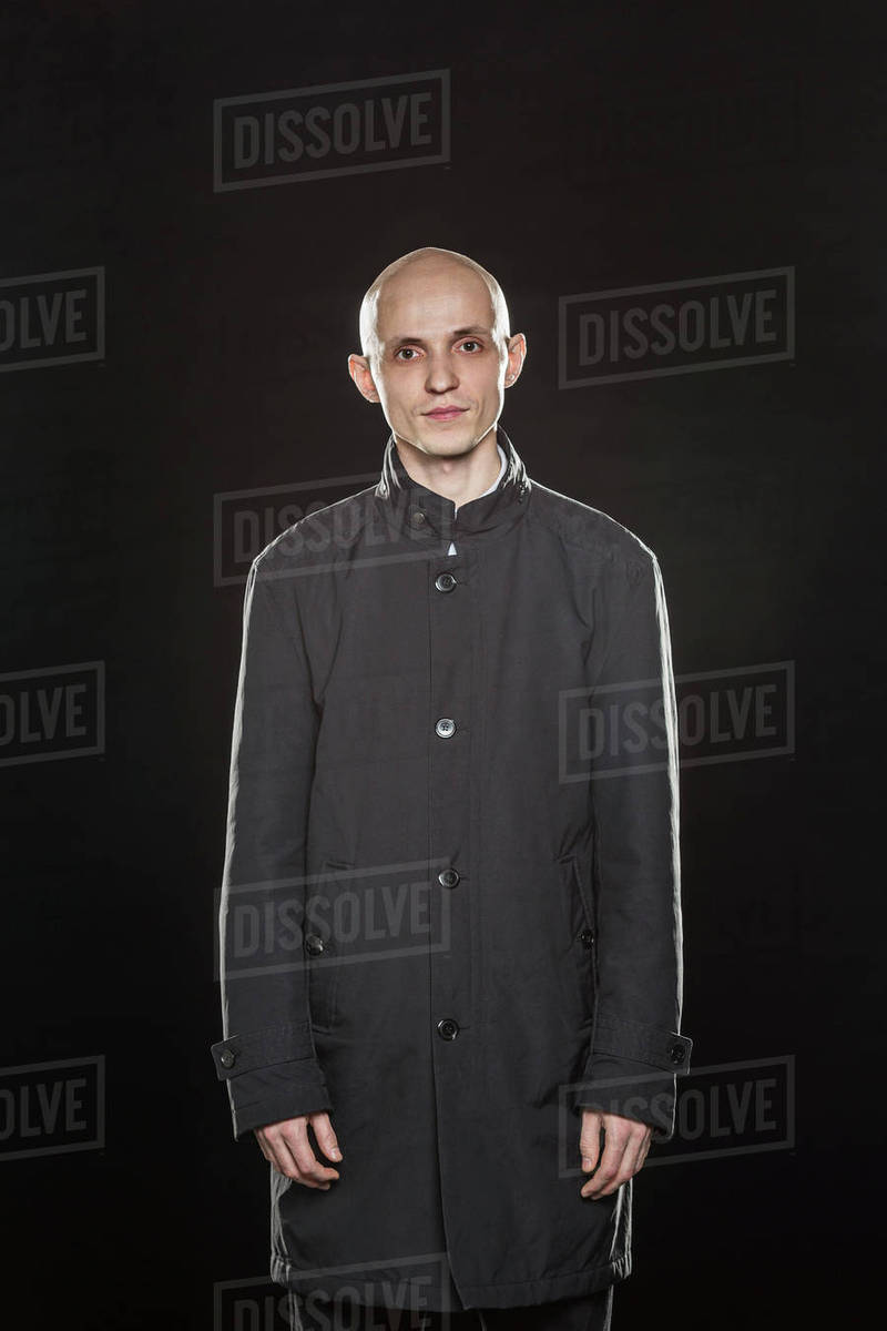Portrait of serious bald man standing against black background - Stock ...