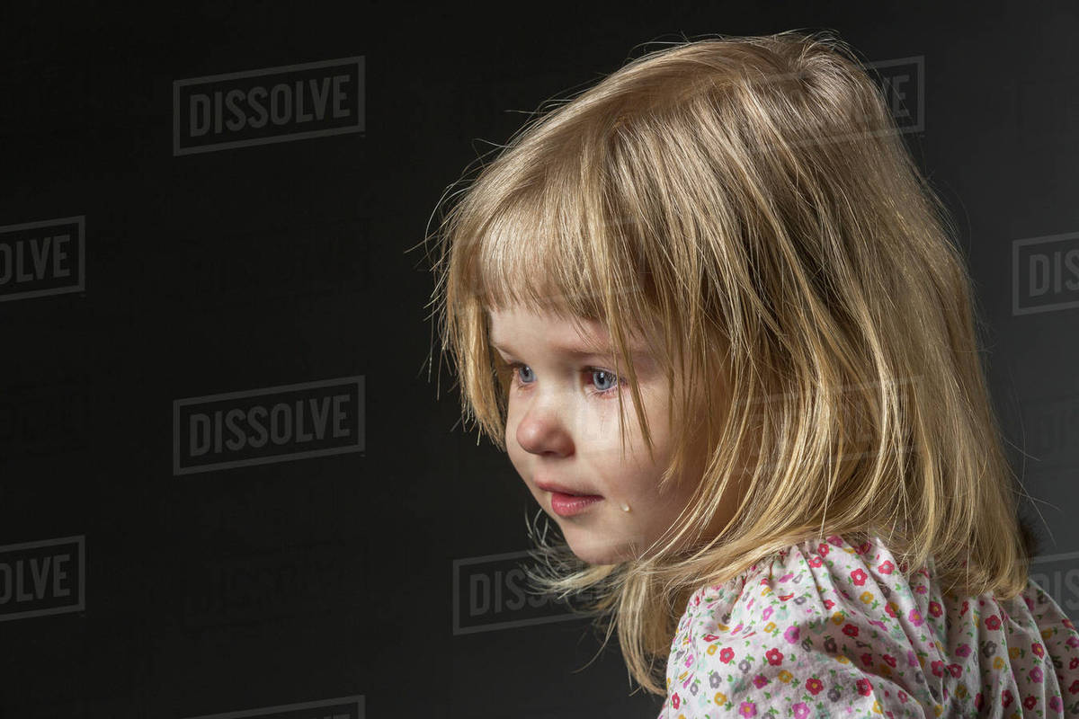 Side view of girl crying against black background - Stock Photo - Dissolve