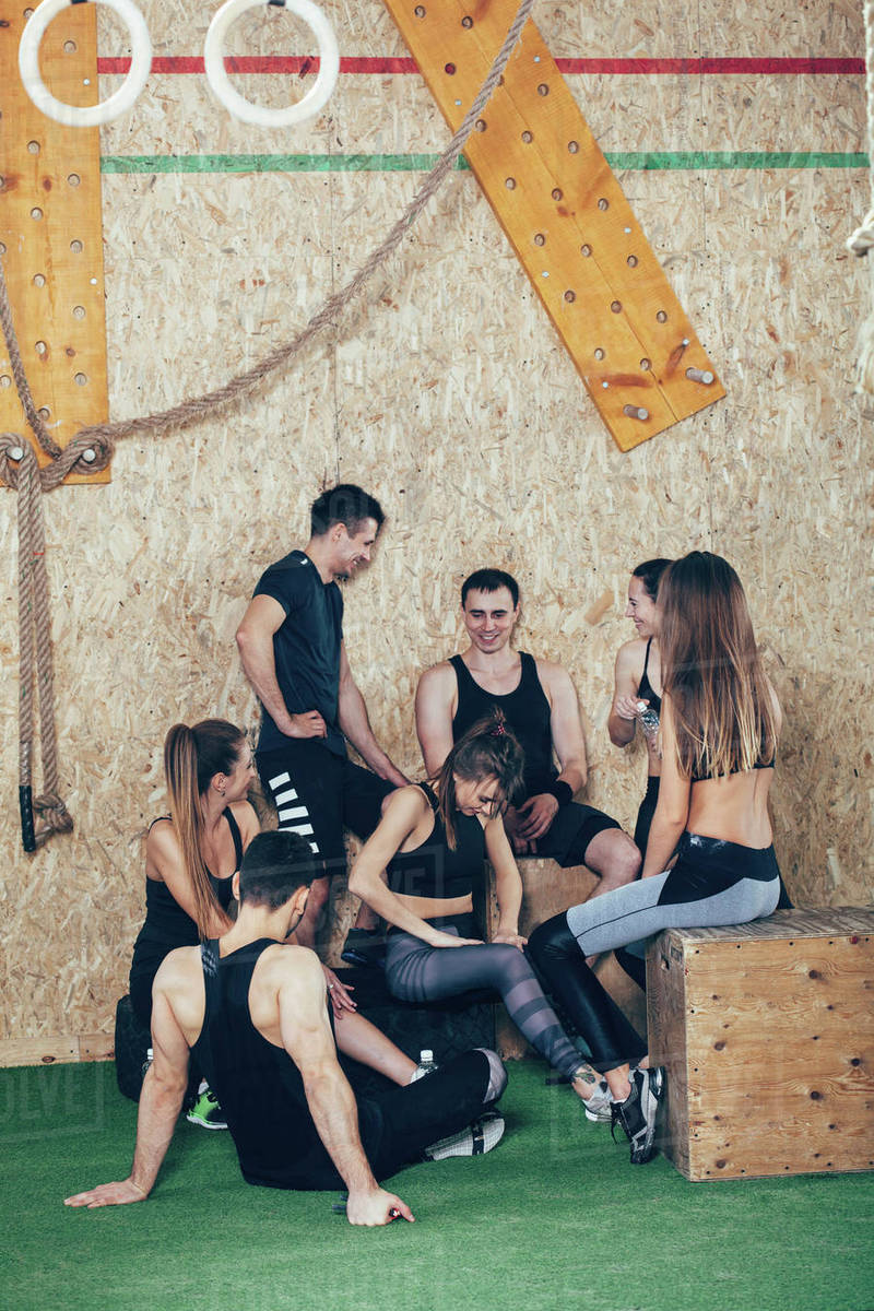 Smiling male and female athletes relaxing after workout at gym ...