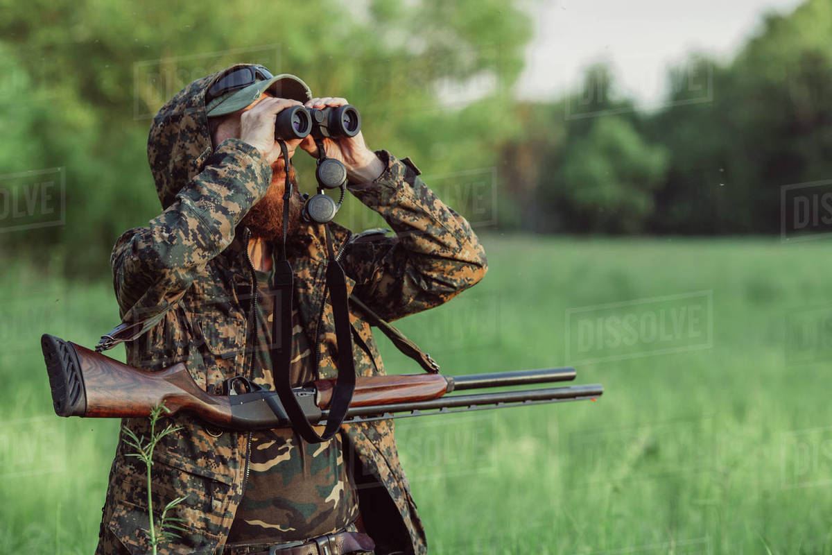 Hunter looking through binoculars on grassy field - Royalty-free Stock ...
