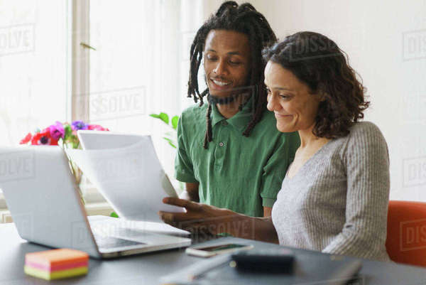 Couple reading documents while sitting with laptop at table - Royalty ...