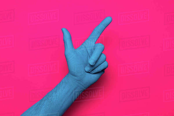 Close-up of blue painted hand pointing against pink background - Stock ...