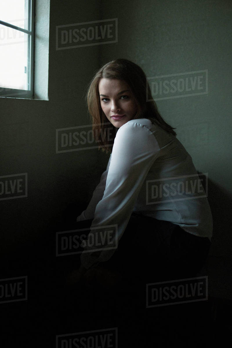 Portrait of beautiful woman sitting by window - Stock Photo - Dissolve