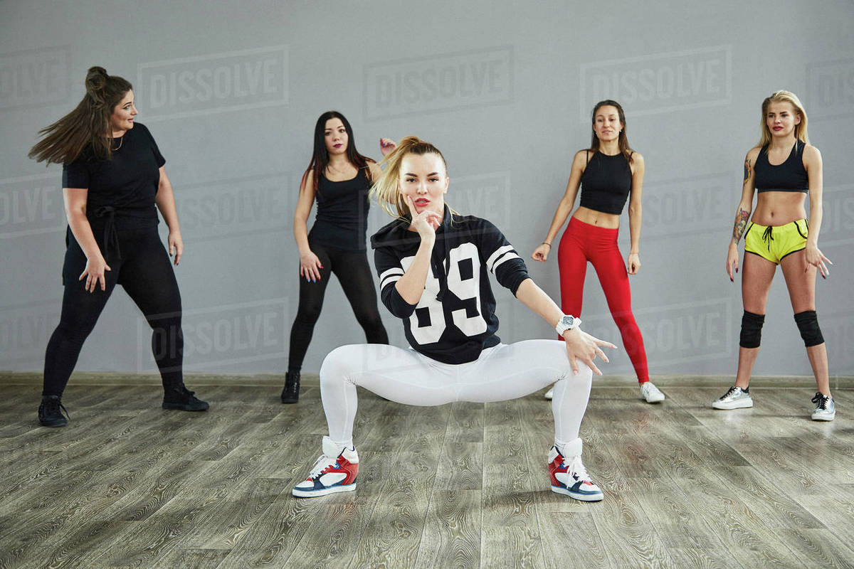 Full length of confident young dancers dancing against wall at studio ...