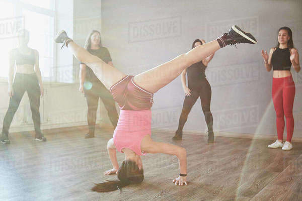 Full length of friends watching at woman practicing headstand while ...