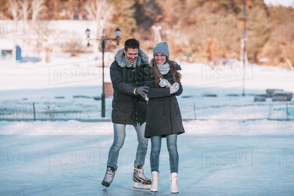 Full length of cheerful couple enjoying ice-skating on rink - Stock ...