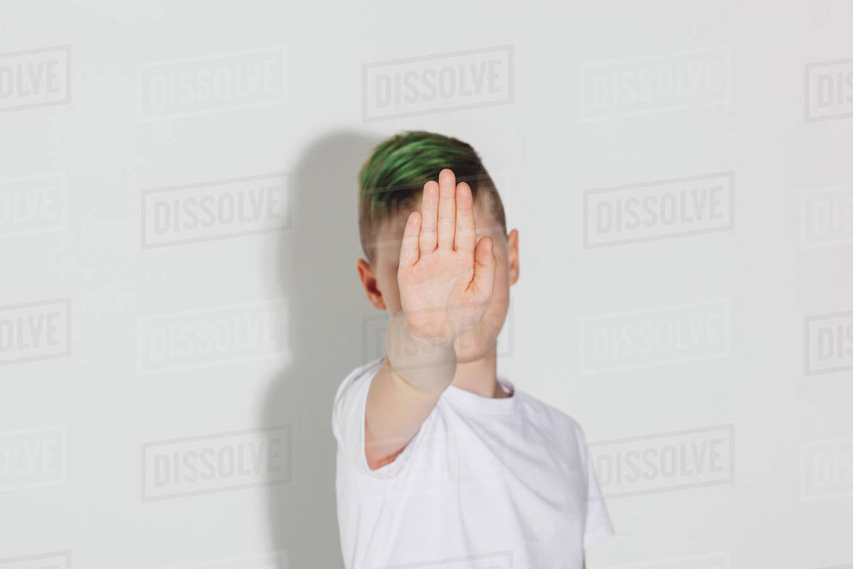 Boy showing stop sign while standing against white background - Stock ...