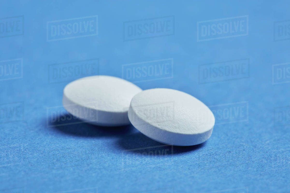 Close up two pills on blue background - Stock Photo - Dissolve