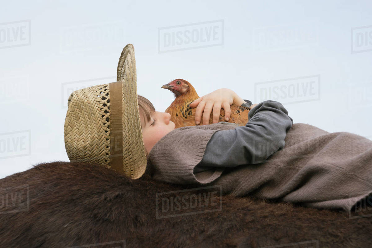 Girl hugging chicken, laying on horse - Stock Photo - Dissolve