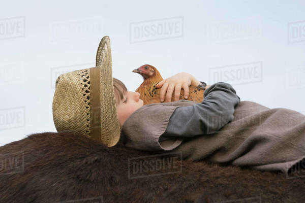 Girl hugging chicken, laying on horse - Royalty-free Stock Photo | Dissolve