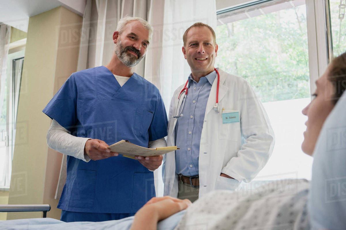 Doctors making rounds, talking with patient in hospital room - Stock ...