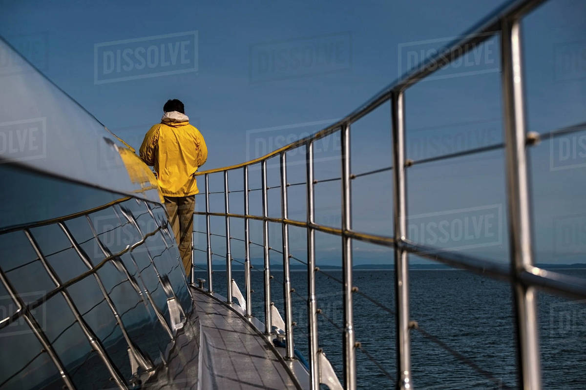 Man standing on deck of boat on sunny ocean - Stock Photo - Dissolve