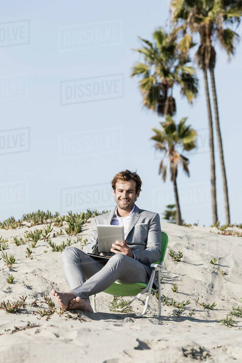 Barefoot businessman using digital tablet on sunny beach, Los Angeles ...
