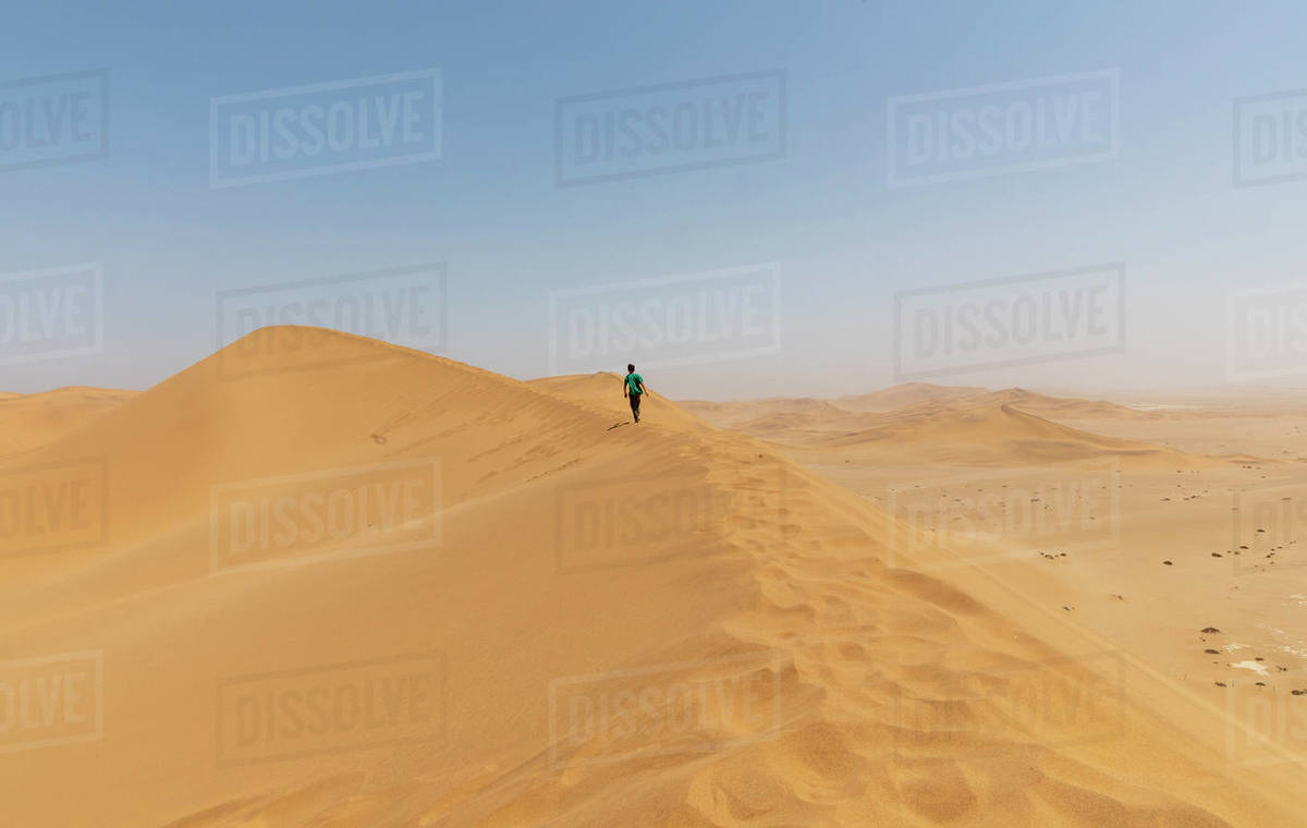 Boy walking along sunny desert sand dune ridge, Namibia - Stock Photo ...