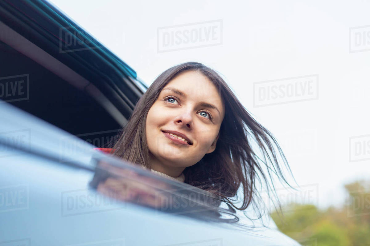 Portrait happy, carefree young woman leaning out car window - Royalty ...