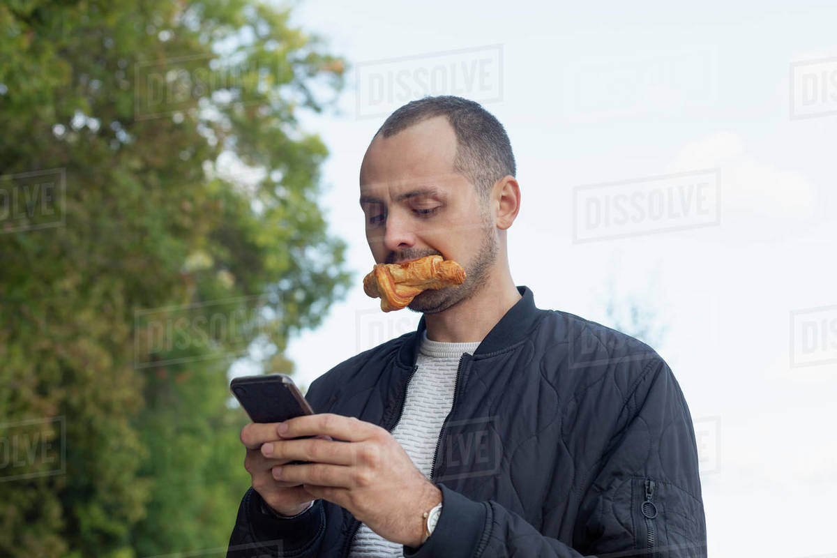 Young man eating and using smart phone - Royalty-free Stock Photo ...