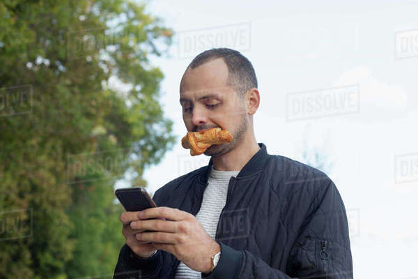Young man eating and using smart phone - Royalty-free Stock Photo ...