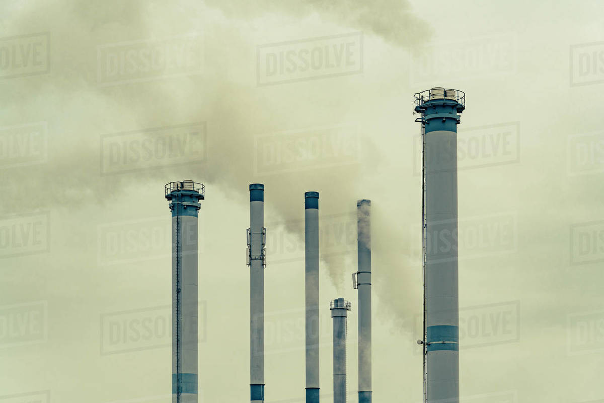 Tall factory smokestacks emitting smoke in sky - Royalty-free Stock ...
